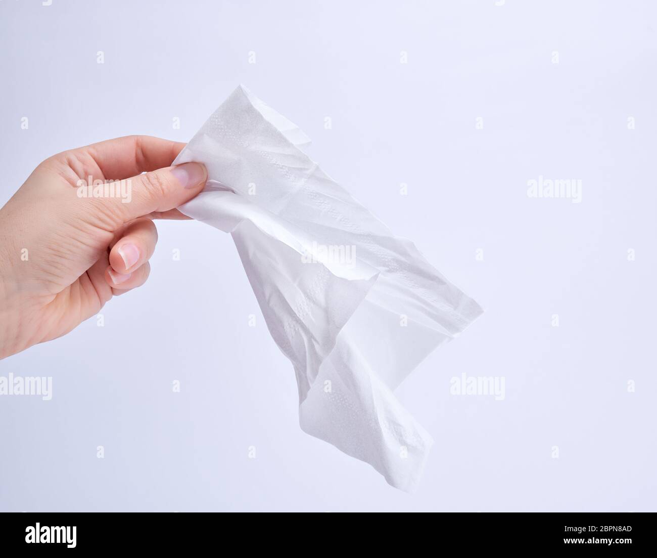 female hand holding a clean white paper napkin for face and body, white ...