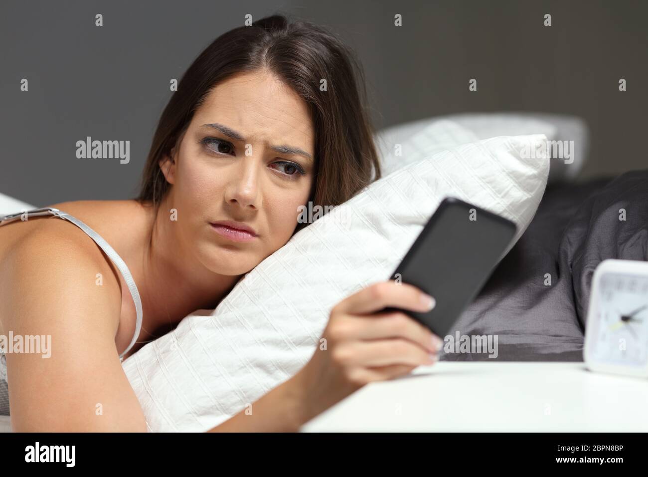 Nervous woman checking smart phone content in the night on a bed Stock ...