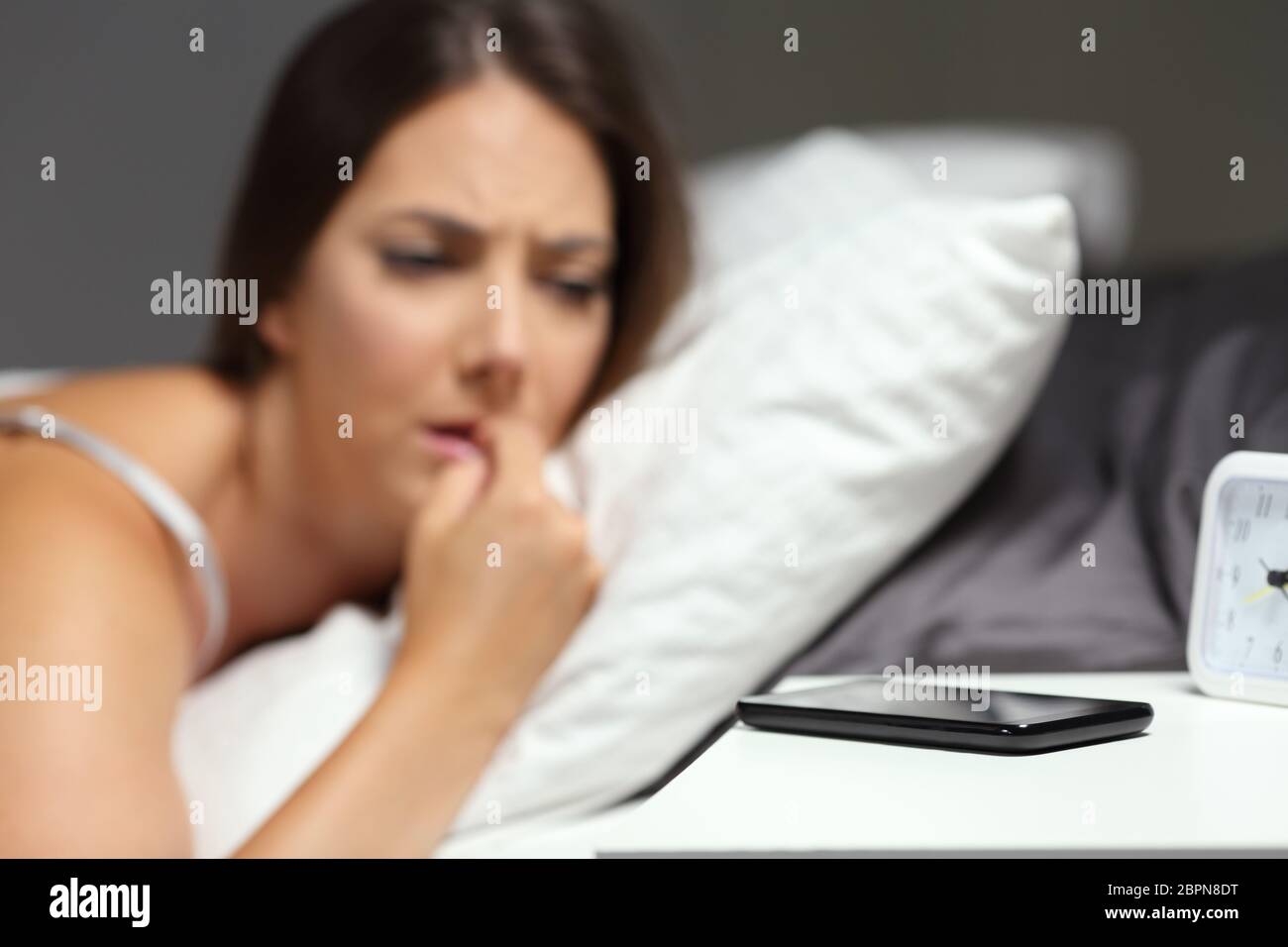 Nervous woman waiting for a phone call on a bed in the night Stock ...