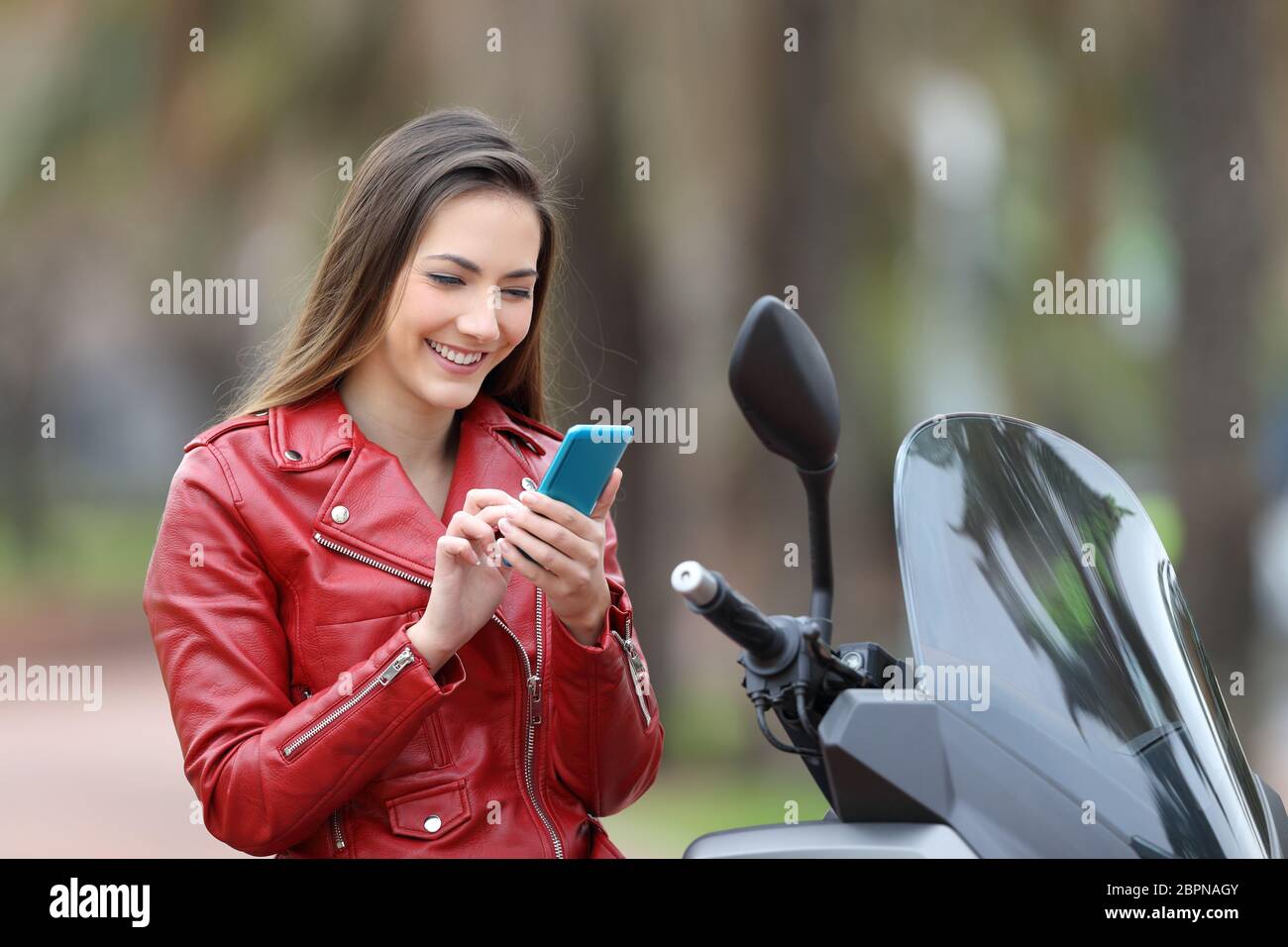 Happy motorbiker using a smart phone sitting on a motorbike Stock Photo ...