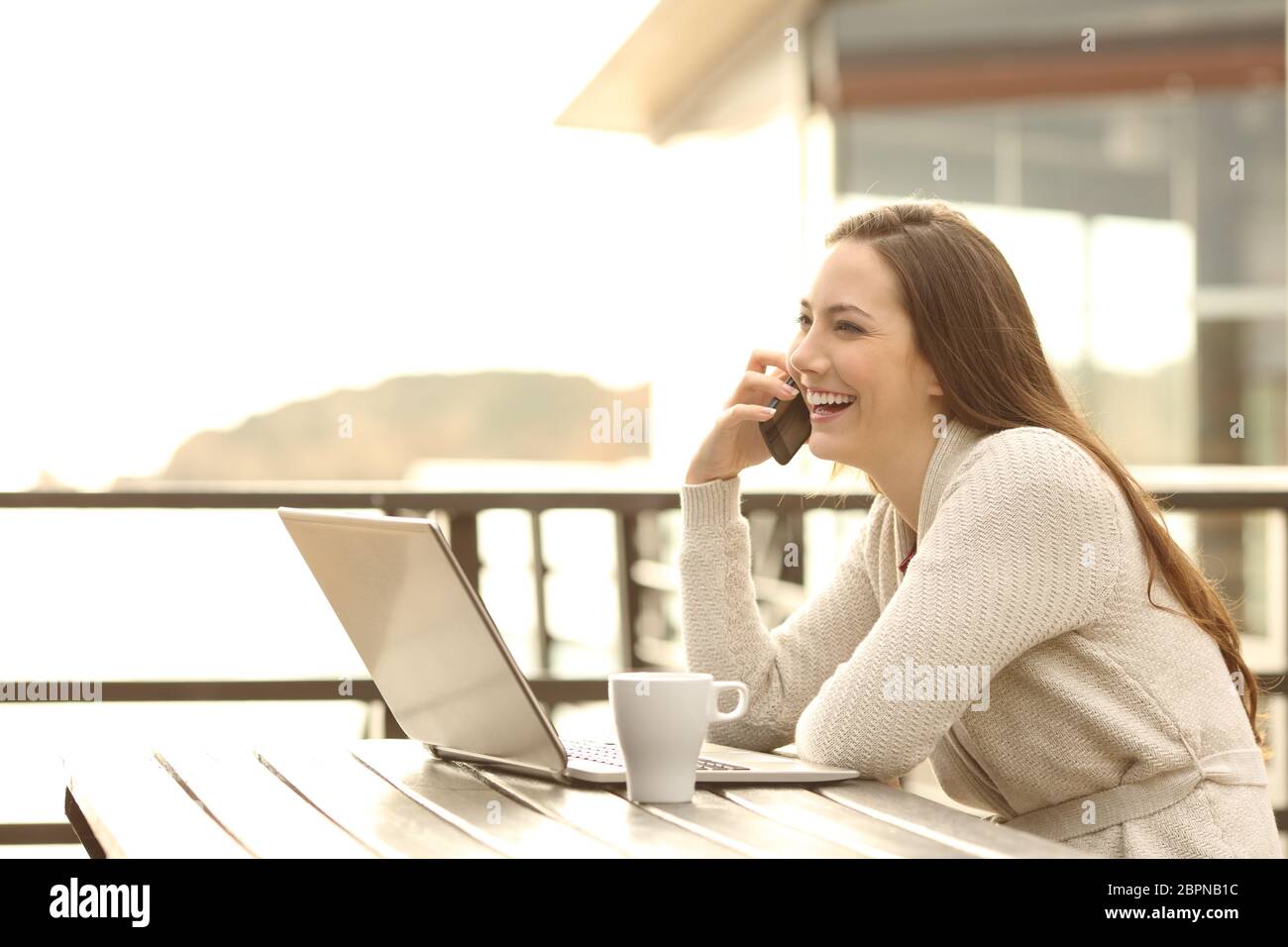 Happy hotel guest on vacation having a phone conversation in a terrace ...