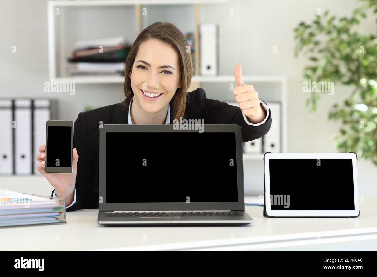 Office worker showing multiple device screens a laptop tablet and phone ...