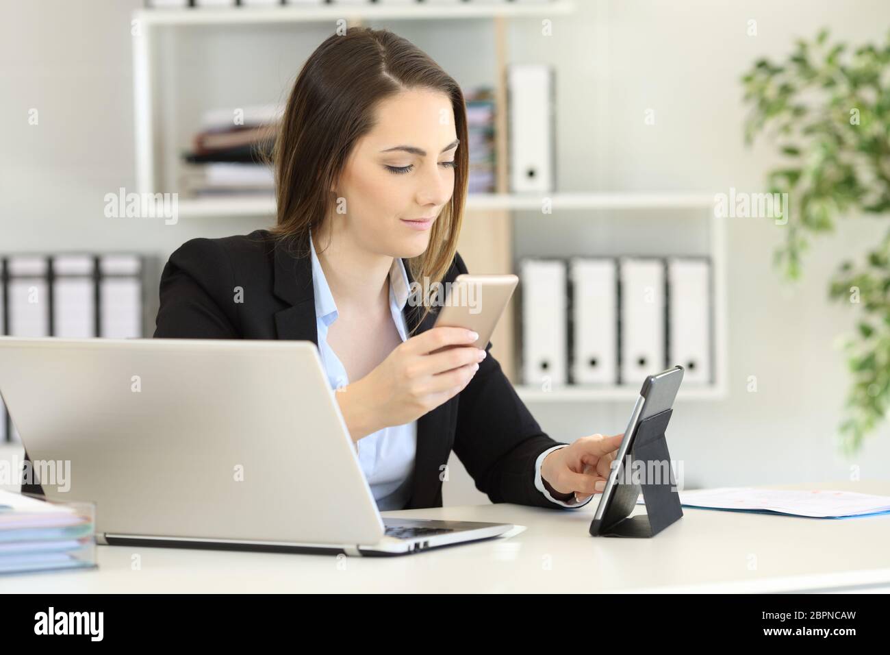 Office worker working with multiple devices on a desktop Stock Photo ...