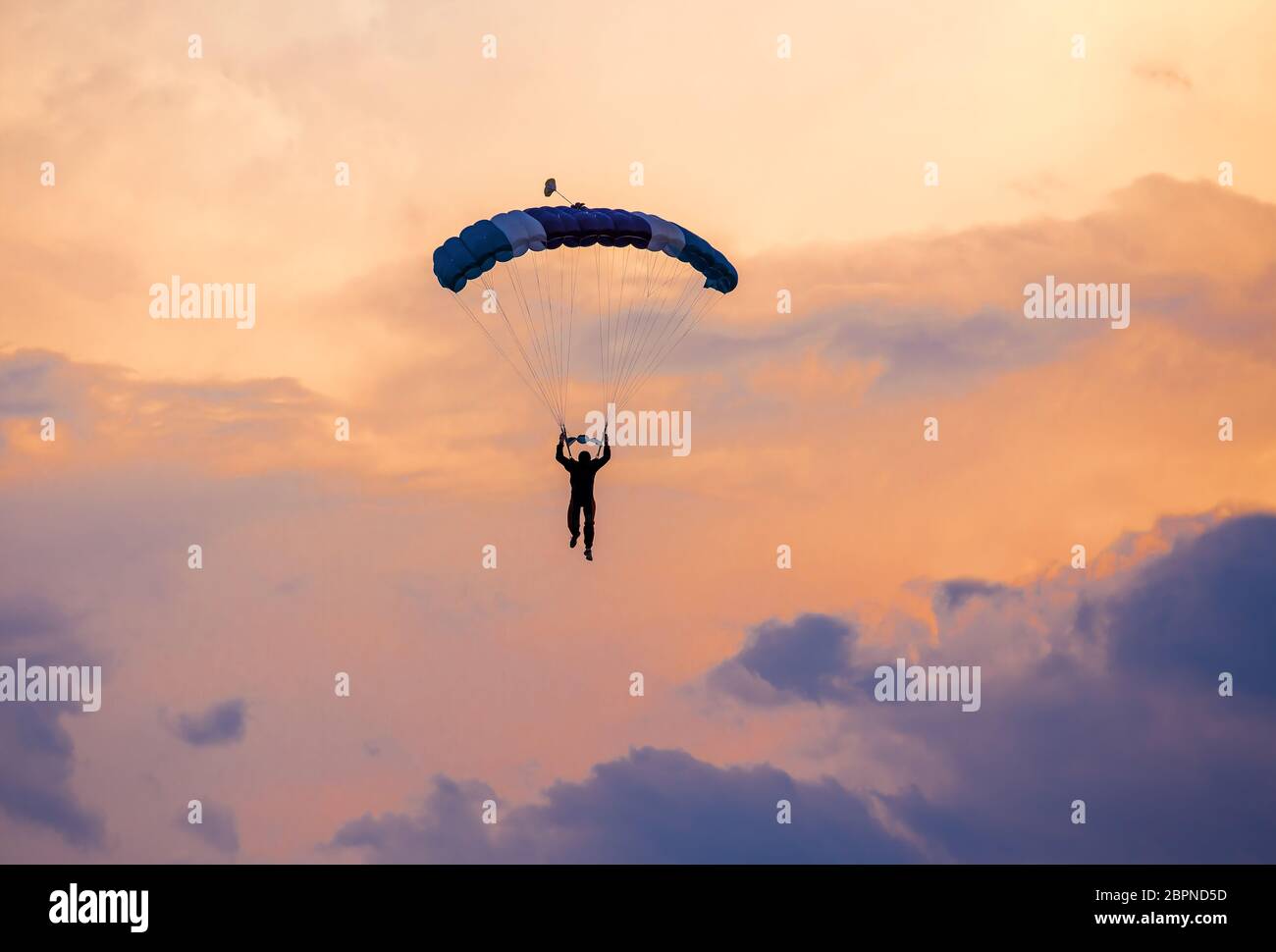 Parachutist falling from the sky in evening sunset dramatic sky ...