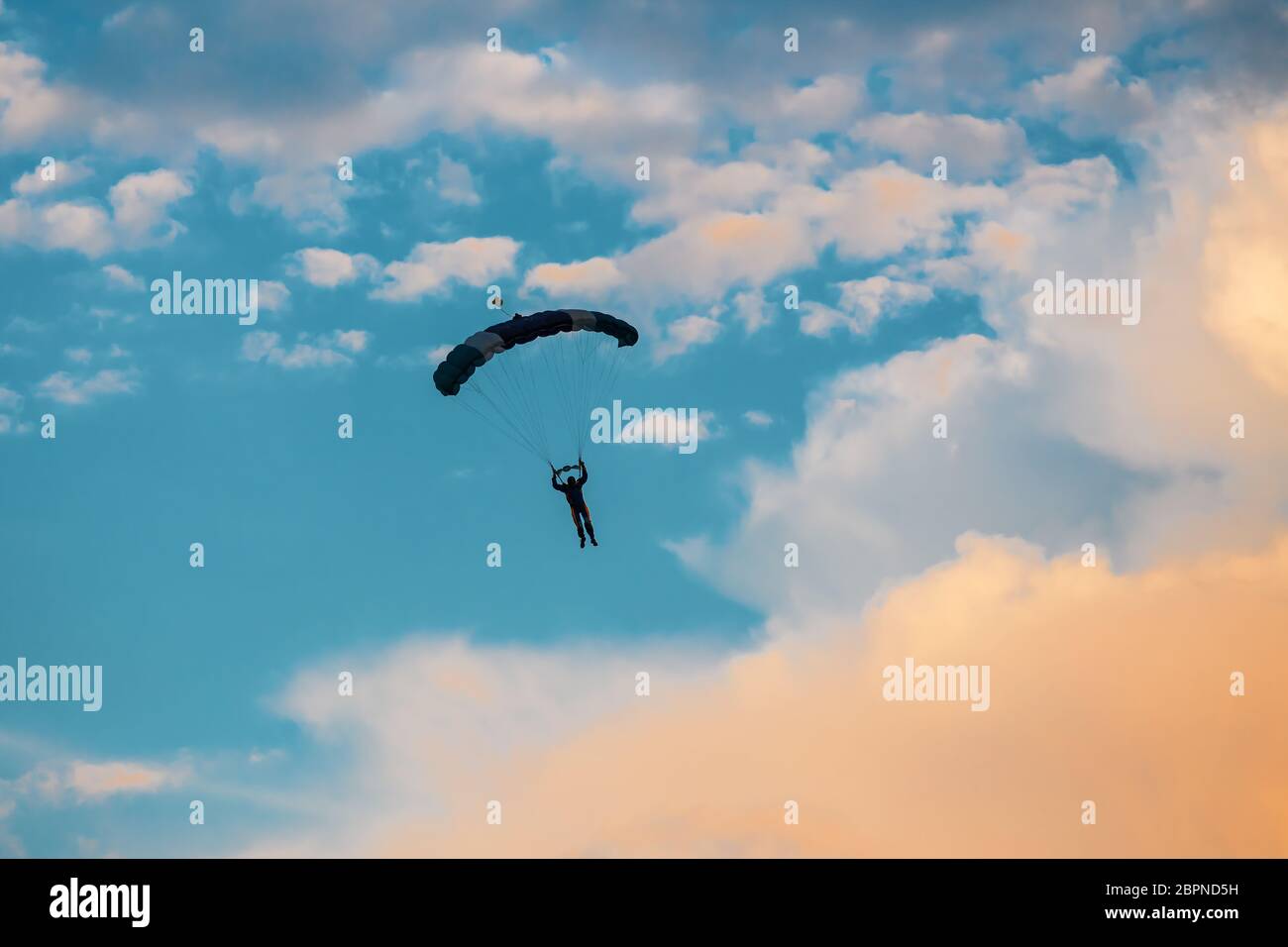 Parachutist falling from the sky in evening sunset dramatic sky ...
