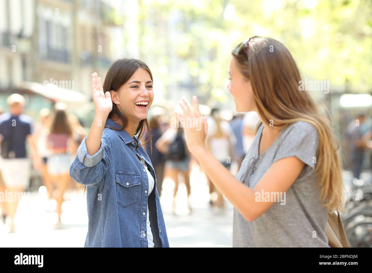 Two happy friends meeting and greeting in the street Stock Photo - Alamy