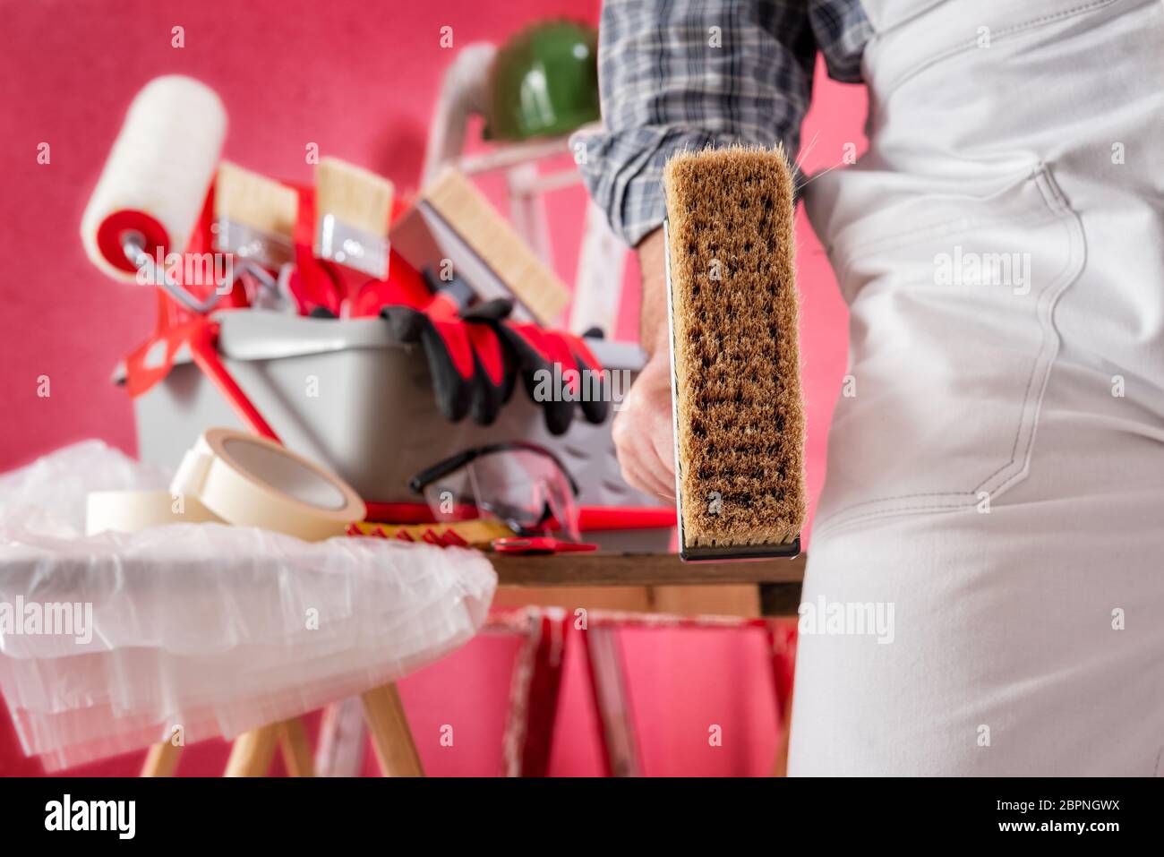 Caucasian house painter worker in white work overalls, holds the brush ...