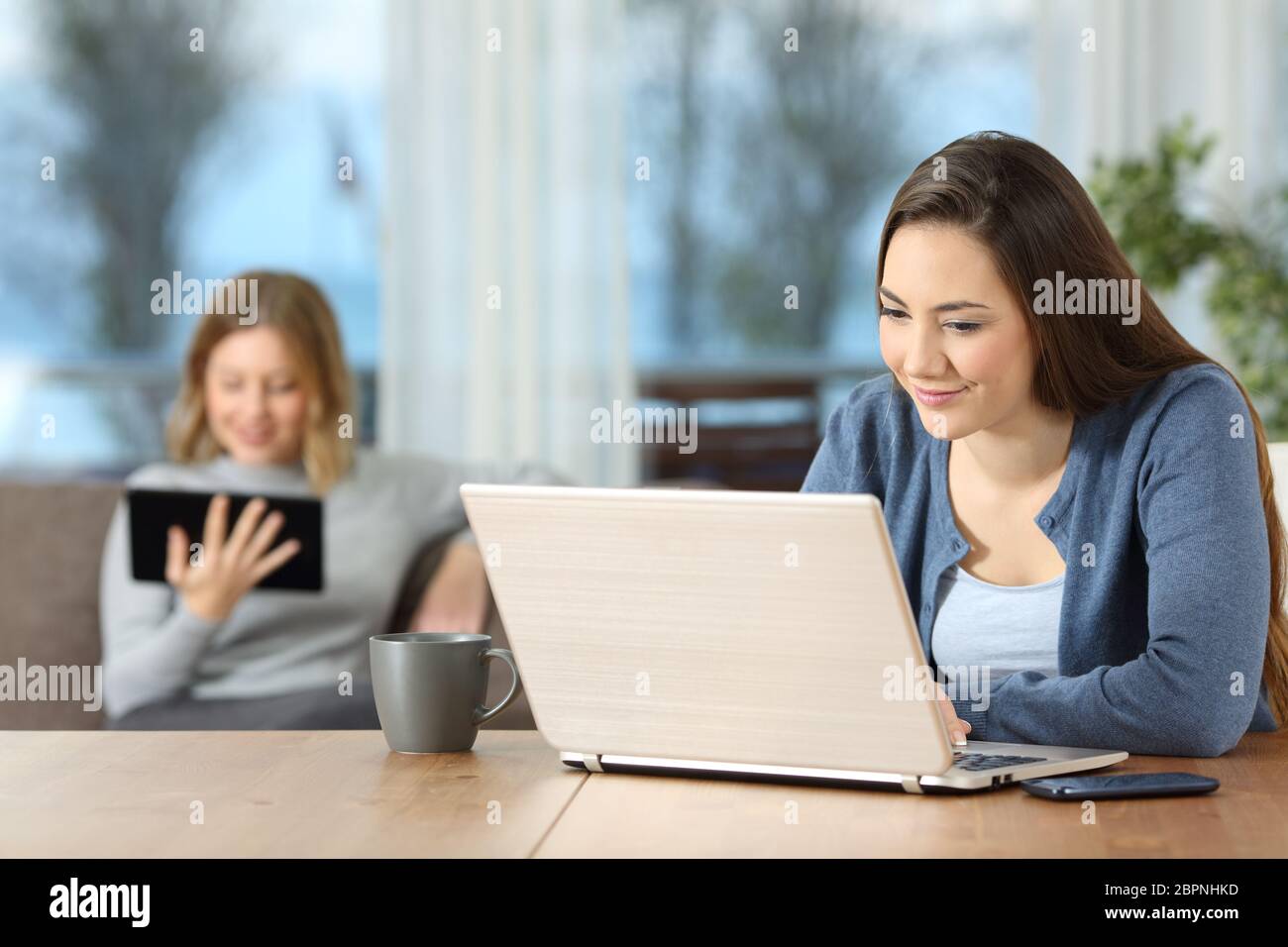Two relaxed roommates using multiple devices with wi fi connection at ...