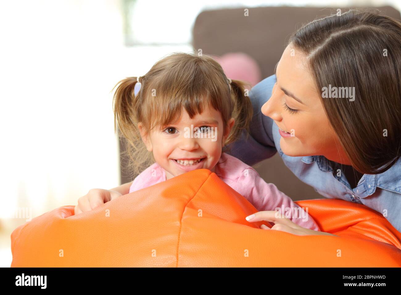 Front view portrait of a baby with her mother looking her beside at ...