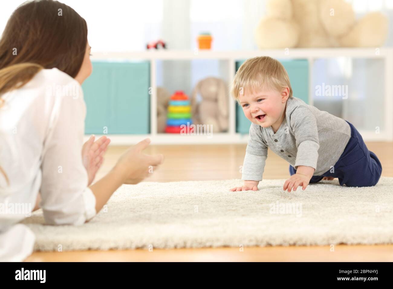 Happy baby crawling towards his mother on a carpet at home Stock Photo ...