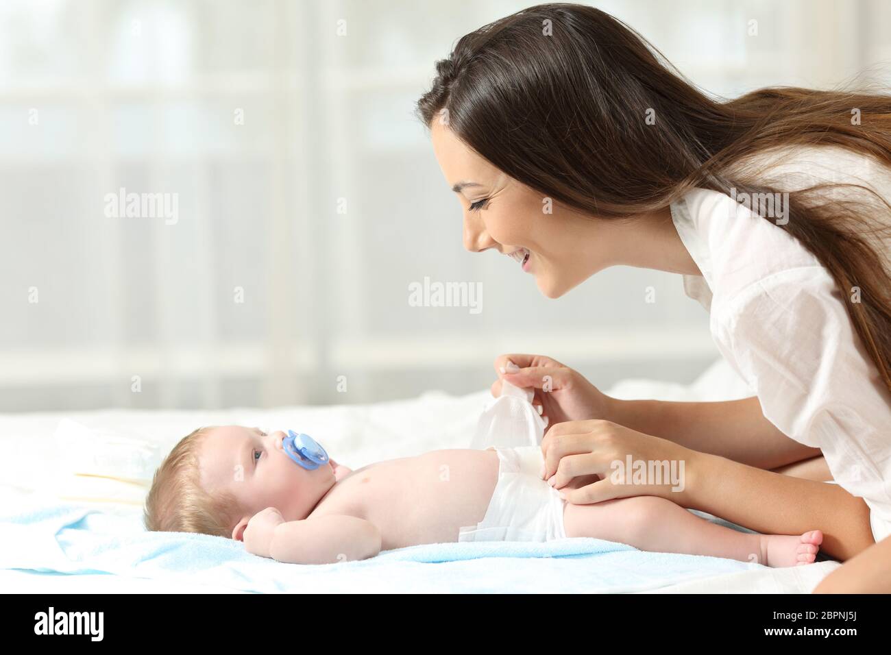 Side view portrait of a happy mother changing diaper to her baby Stock ...