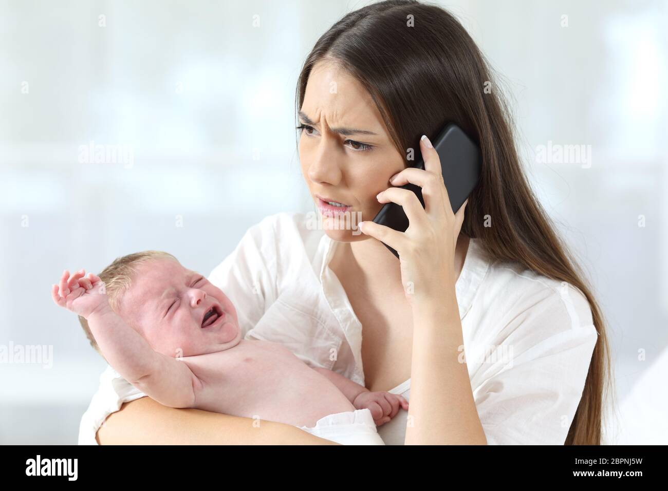 Mother calling to a doctor on phone worried about her baby crying ...