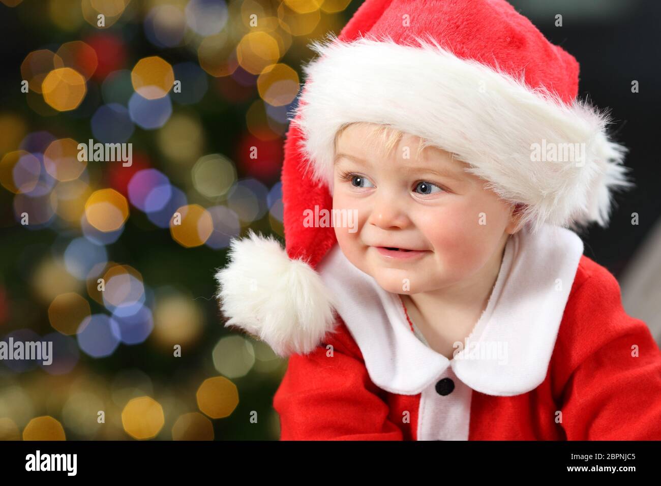Portrait of a baby wearing santa disguise looking at side on a couch at ...