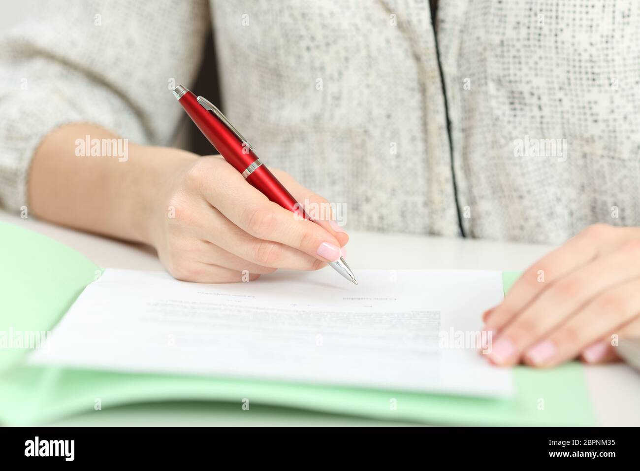 Close up front view portrait of a hand signing a contract on a desktop ...