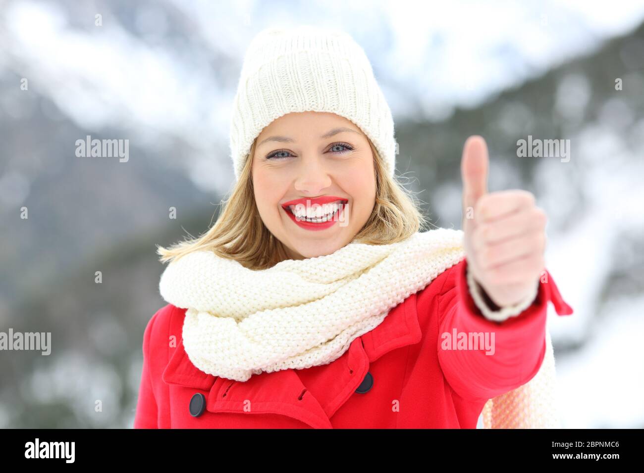 Front view portrait of a woman in red with thumbs up in winter with a ...