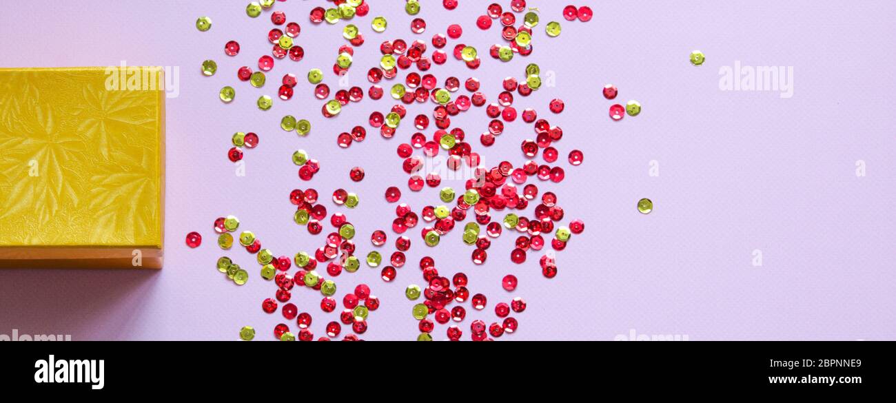 Yellow open gift box with party confetti on a pink background. Flat lay ...