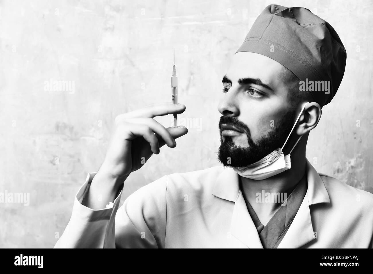 Doctor with beard and assured face expression in lab coat looks at ...