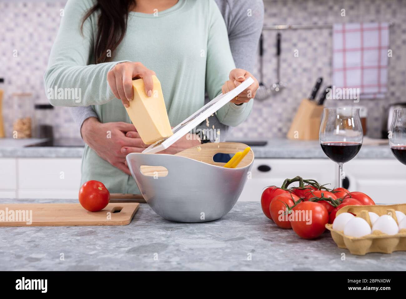 Mid-section Of Woman Grating Butter While Husband Hugging In Kitchen ...