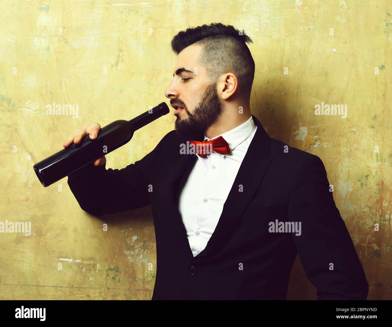 Young classy man with tired face expression drinks alcoholic beverage ...