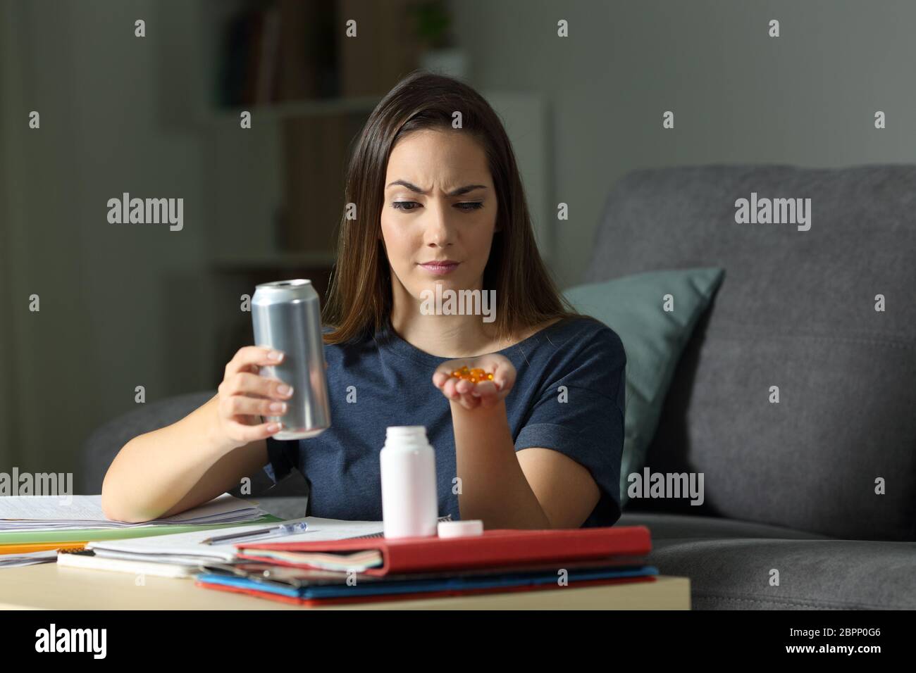 Suspicious student comparing vitamin pill supplement and energy drink ...