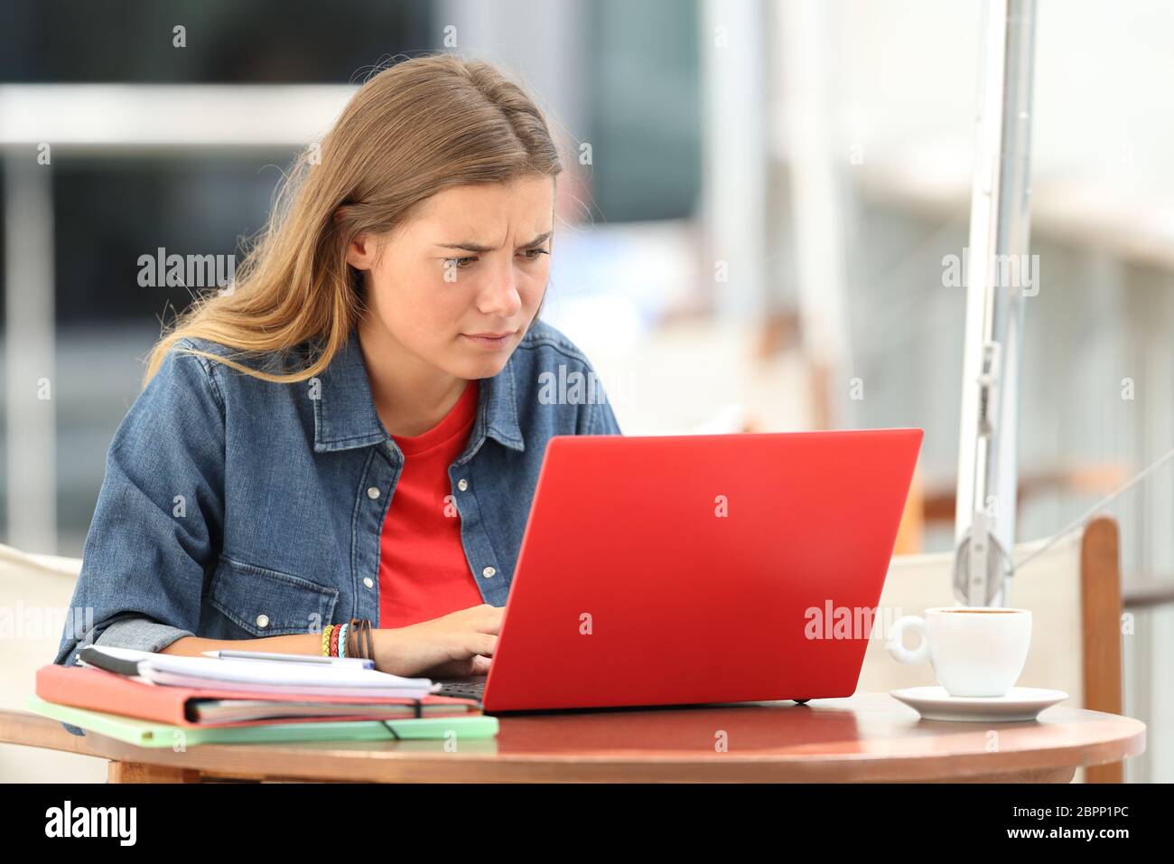 Single confused student searching on line with a red laptop sitting in ...