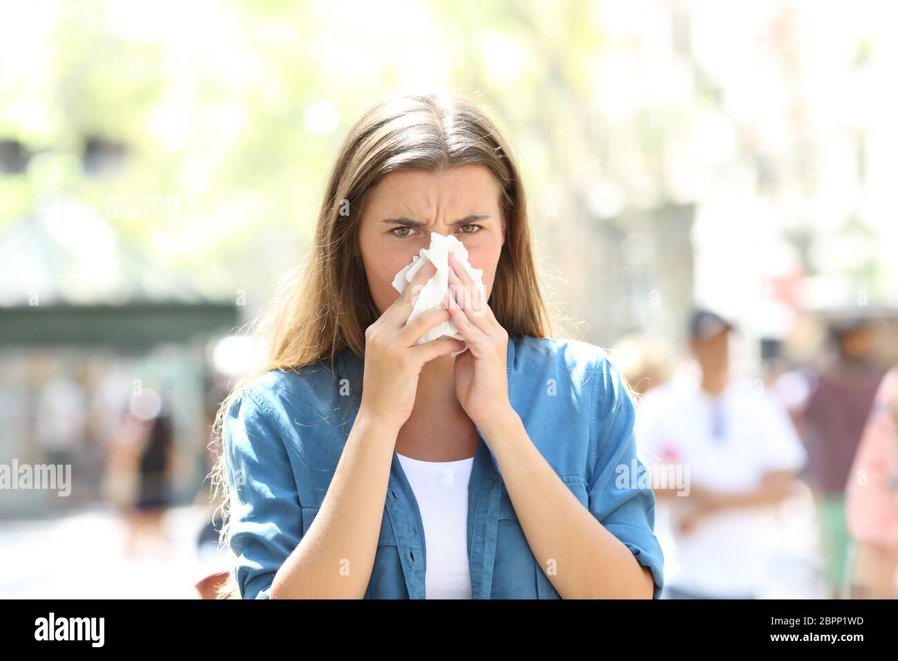 Front view of an ill or allergic woman blowing mucus looking at camera ...
