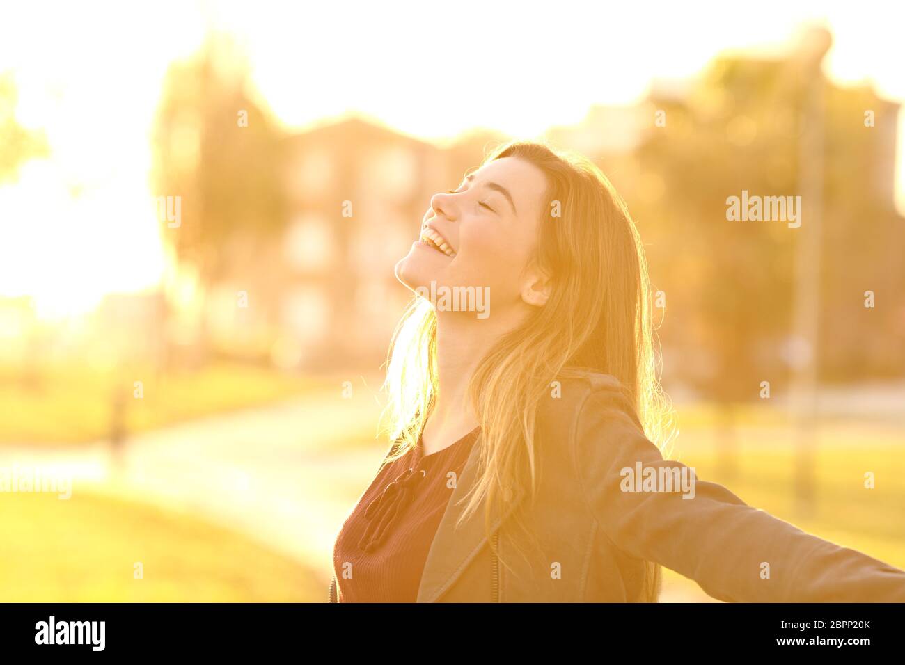 Back light portrait of a happy single teen girl breathing fresh air at ...