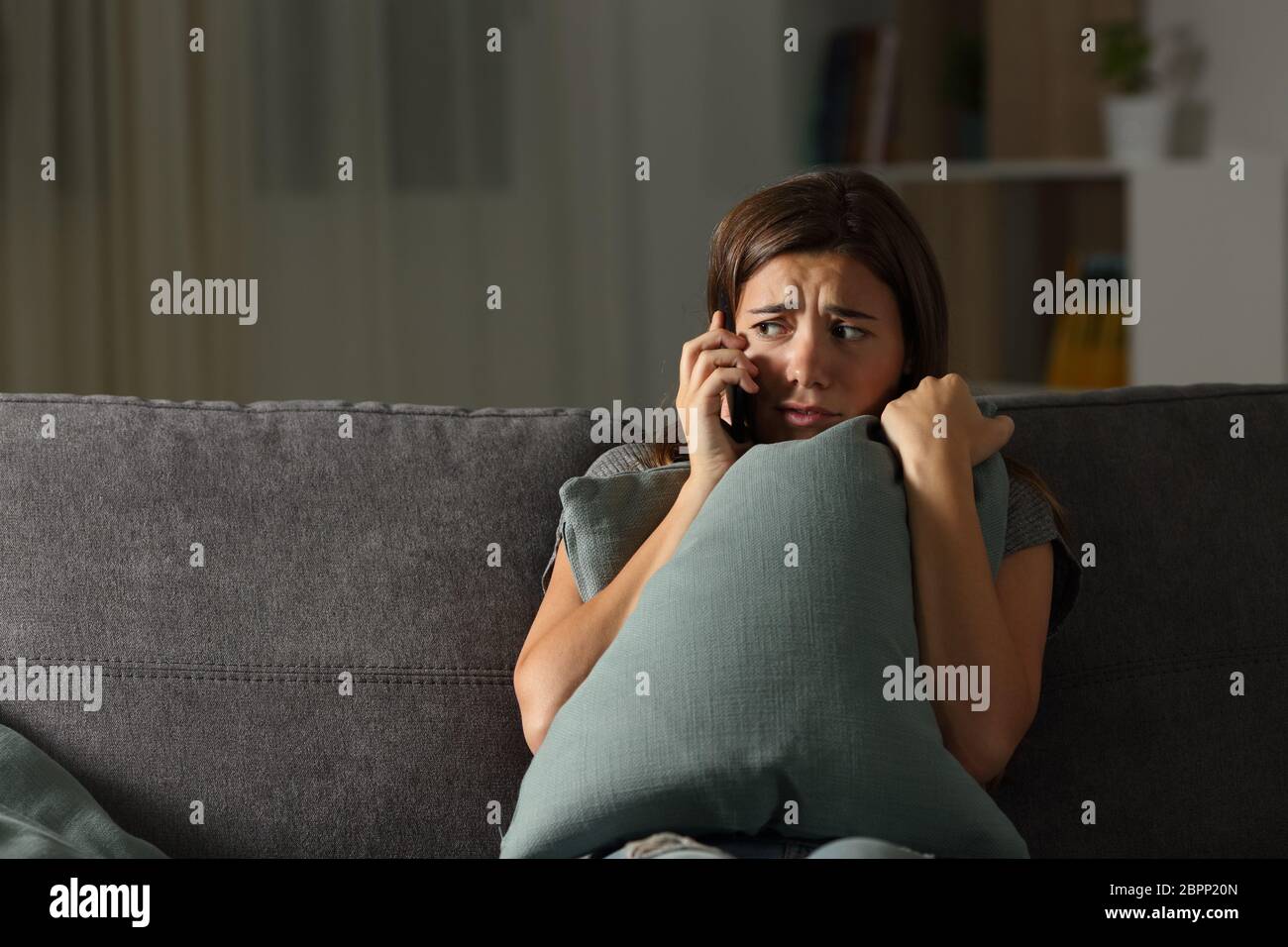 Scared teen calling police sitting on a couch in the living room at ...