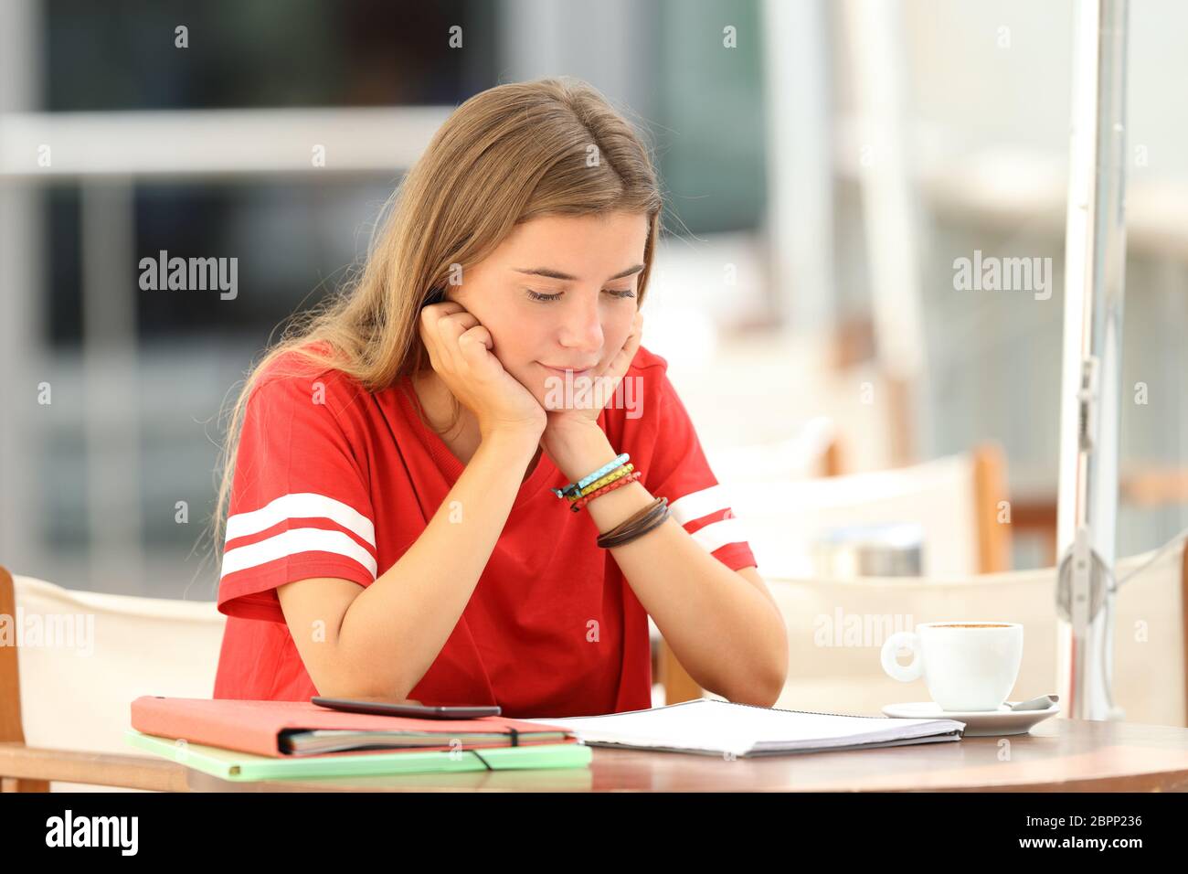 Single student studying and memorizing notes sitting in a bar terrace ...