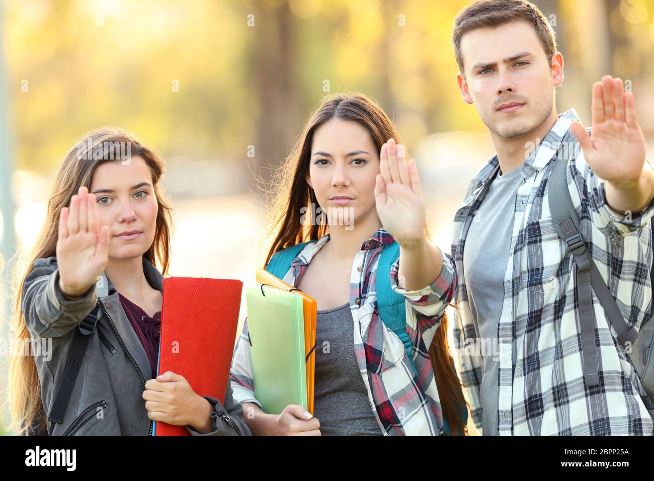 Three angry students gesturing stop in a park Stock Photo - Alamy