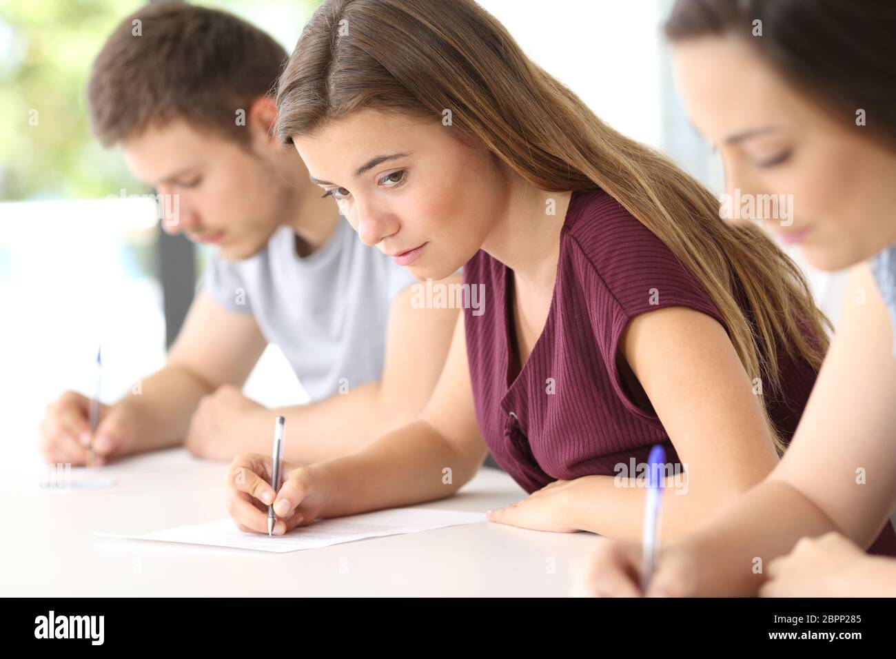 Student trying to copy from a classmate during an exam Stock Photo - Alamy