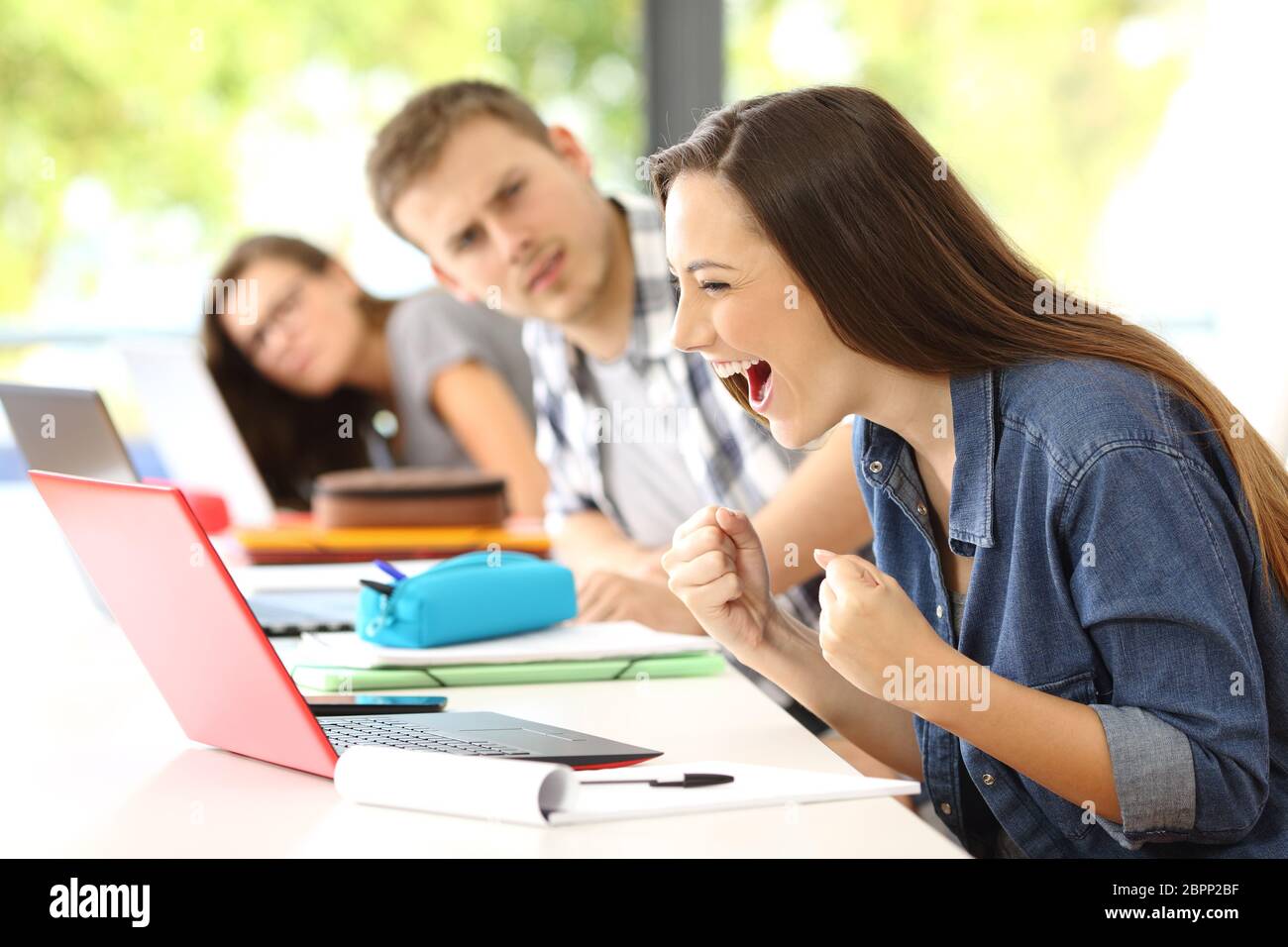 Excited student receiving good news on line in a classroom with her ...