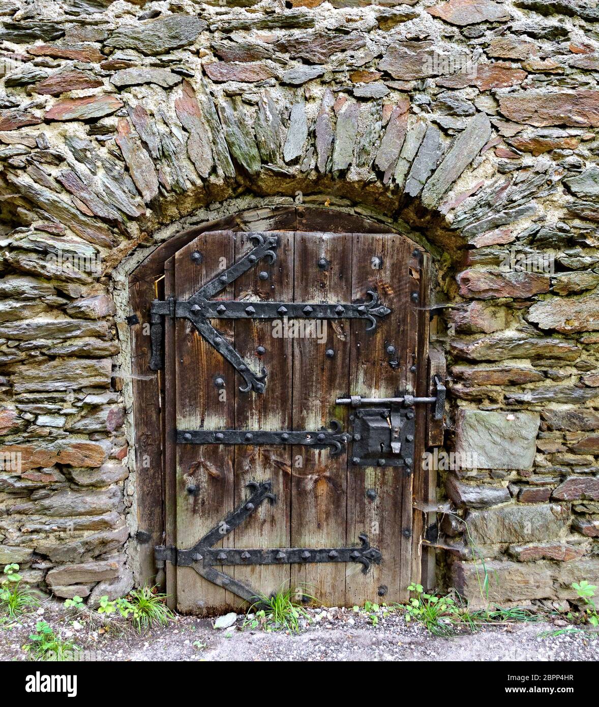 old wooden door with iron fittings in a natural stone wall at the ...