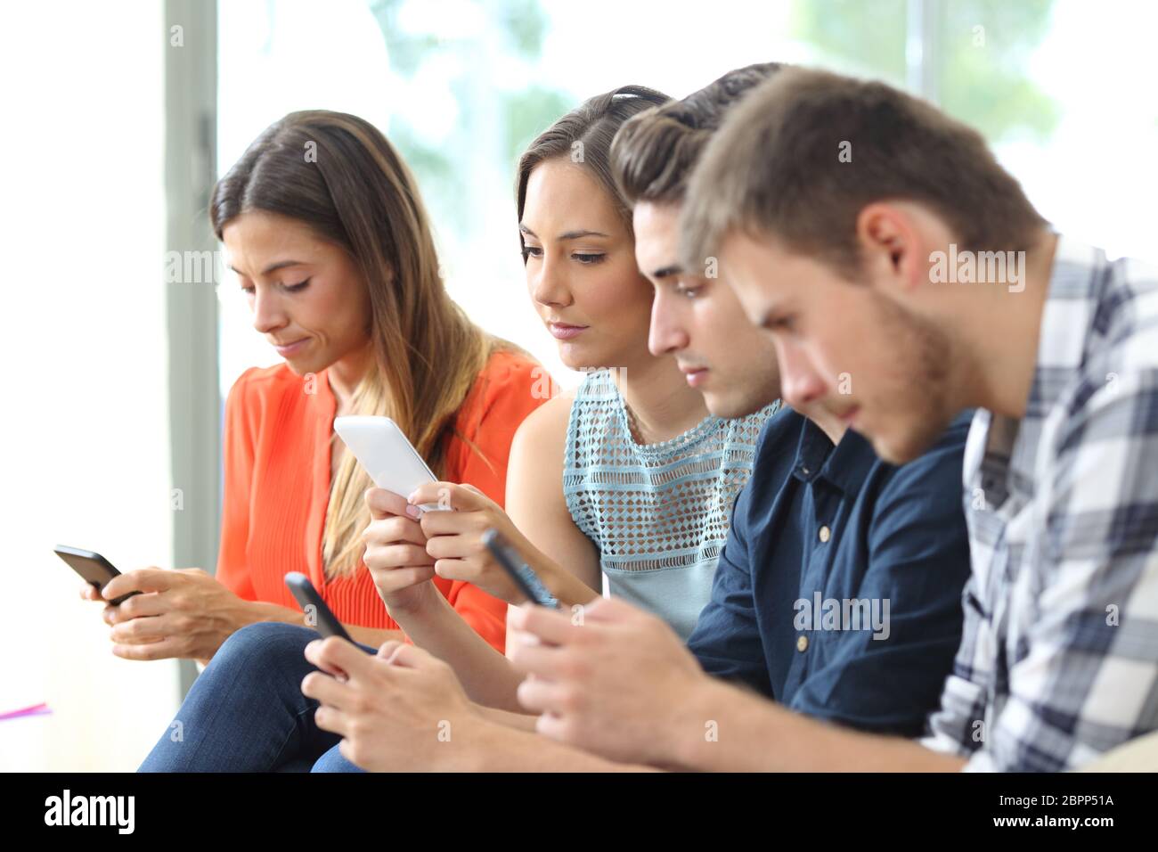 Addicted group of friends using their smart phones at the same time at ...