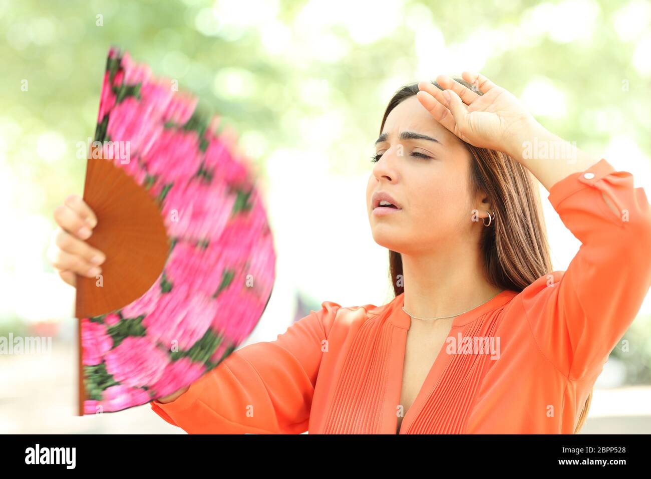 Overwhelmed girl suffering heat stroke fanning in the street in summer ...