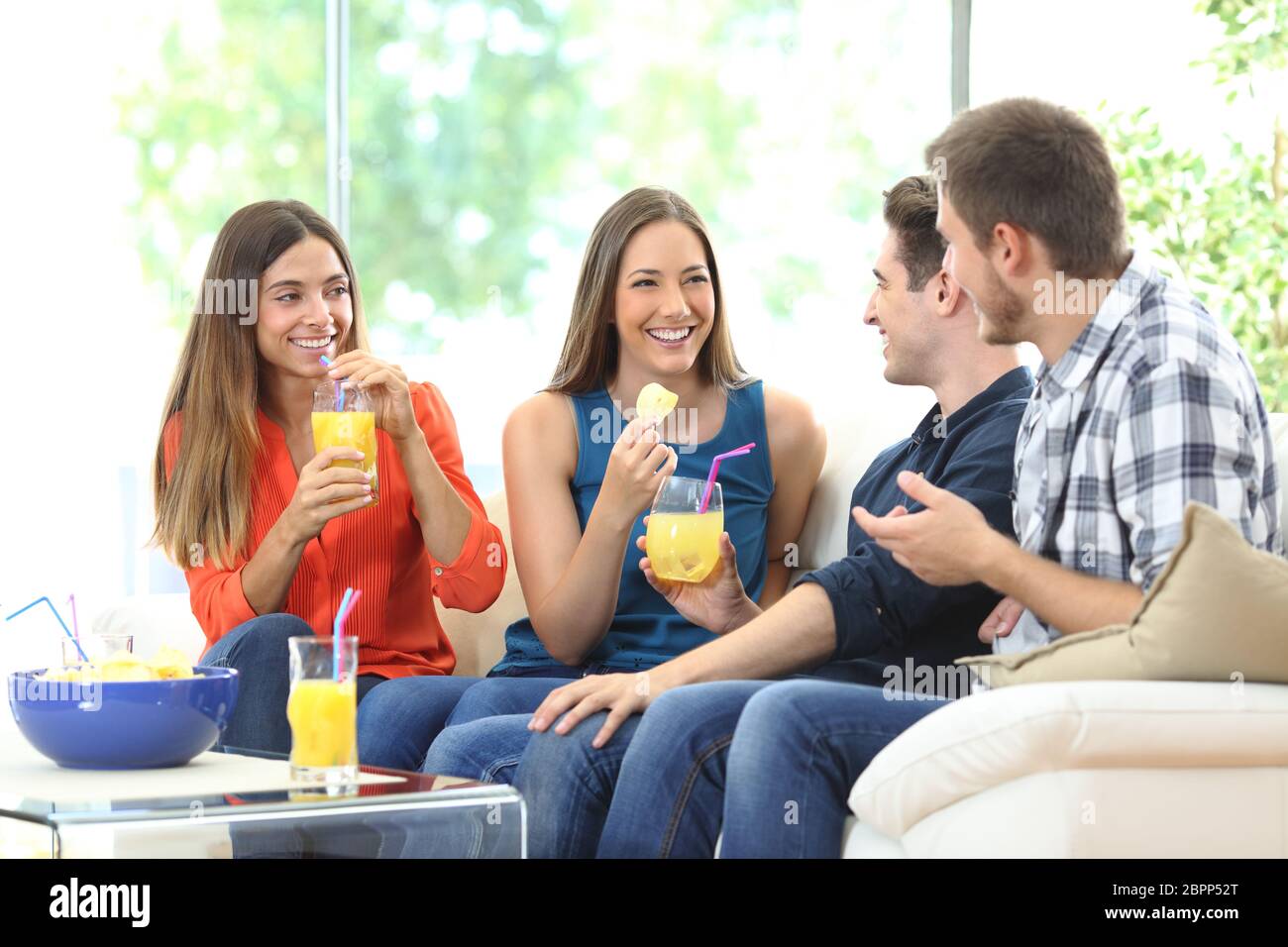 Group of happy friends talking eating chips and drinking refreshments ...