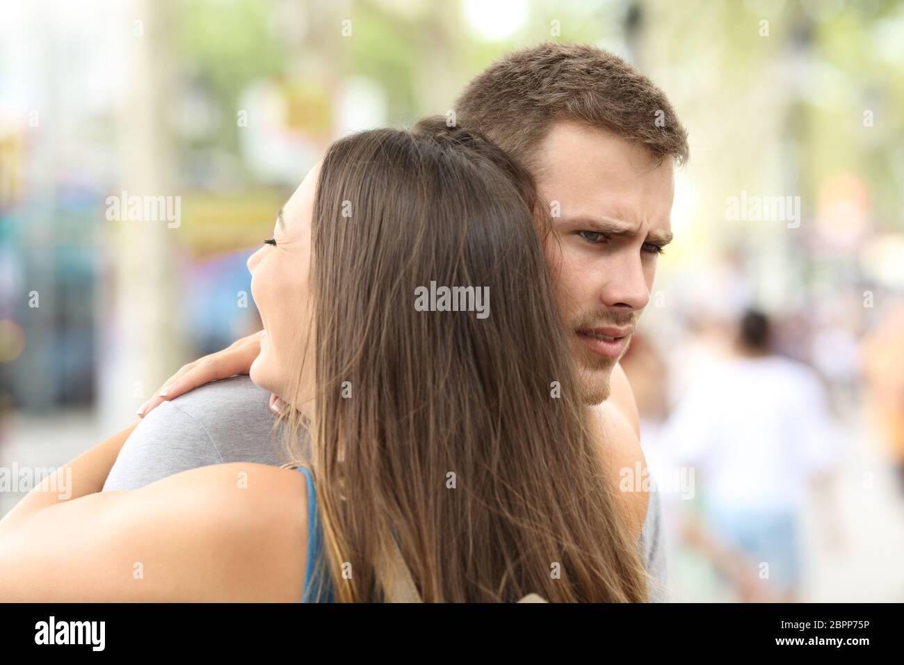 Discontent boyfriend hugging his partner on the street Stock Photo - Alamy