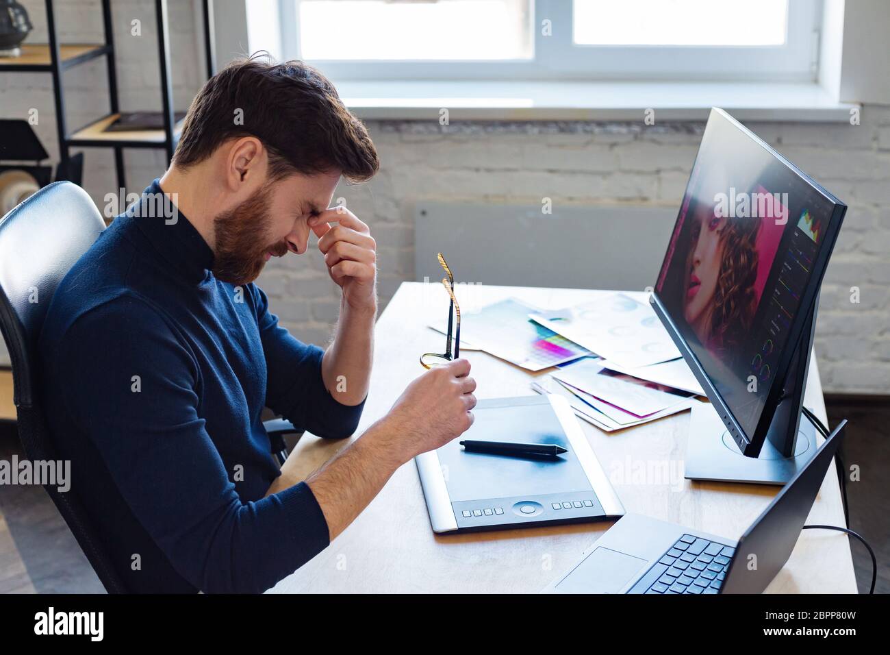 Portrait of tired graphic designer working overtime in office. Stressed ...