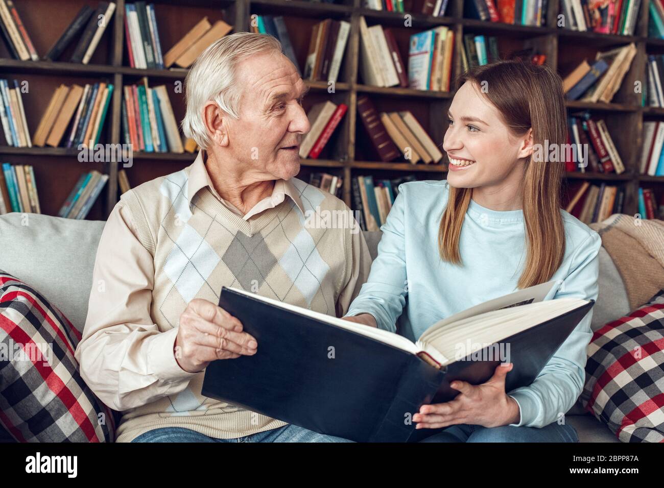 Father and daughter at home library sitting holding photo album ...