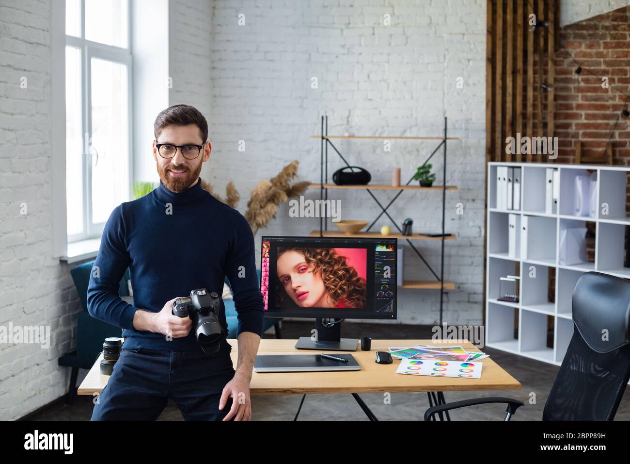 Portrait of professional photographer holding camera in photo studio ...