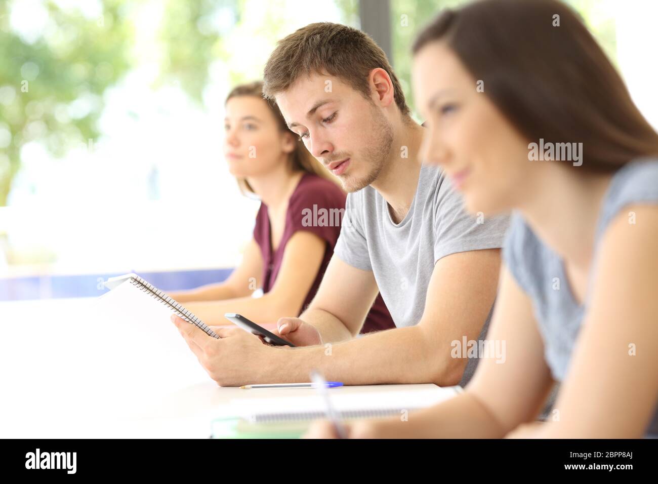 Student distracted with a mobile phone during a class in a classroom ...