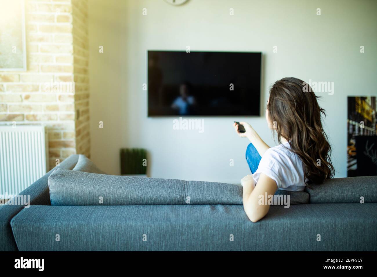 Young woman changing channels with remote control Stock Photo - Alamy