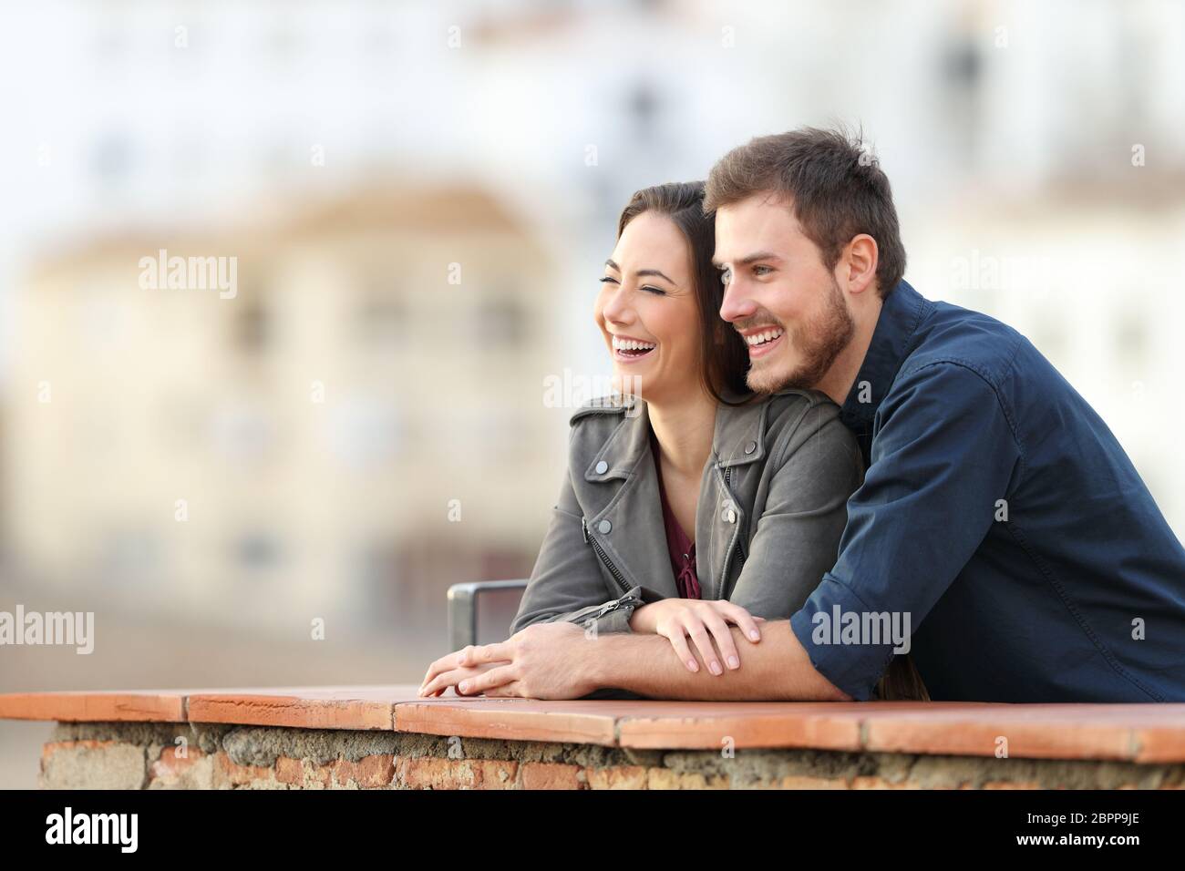 Happy couple enjoying views in a rural apartment terrace on vacation ...