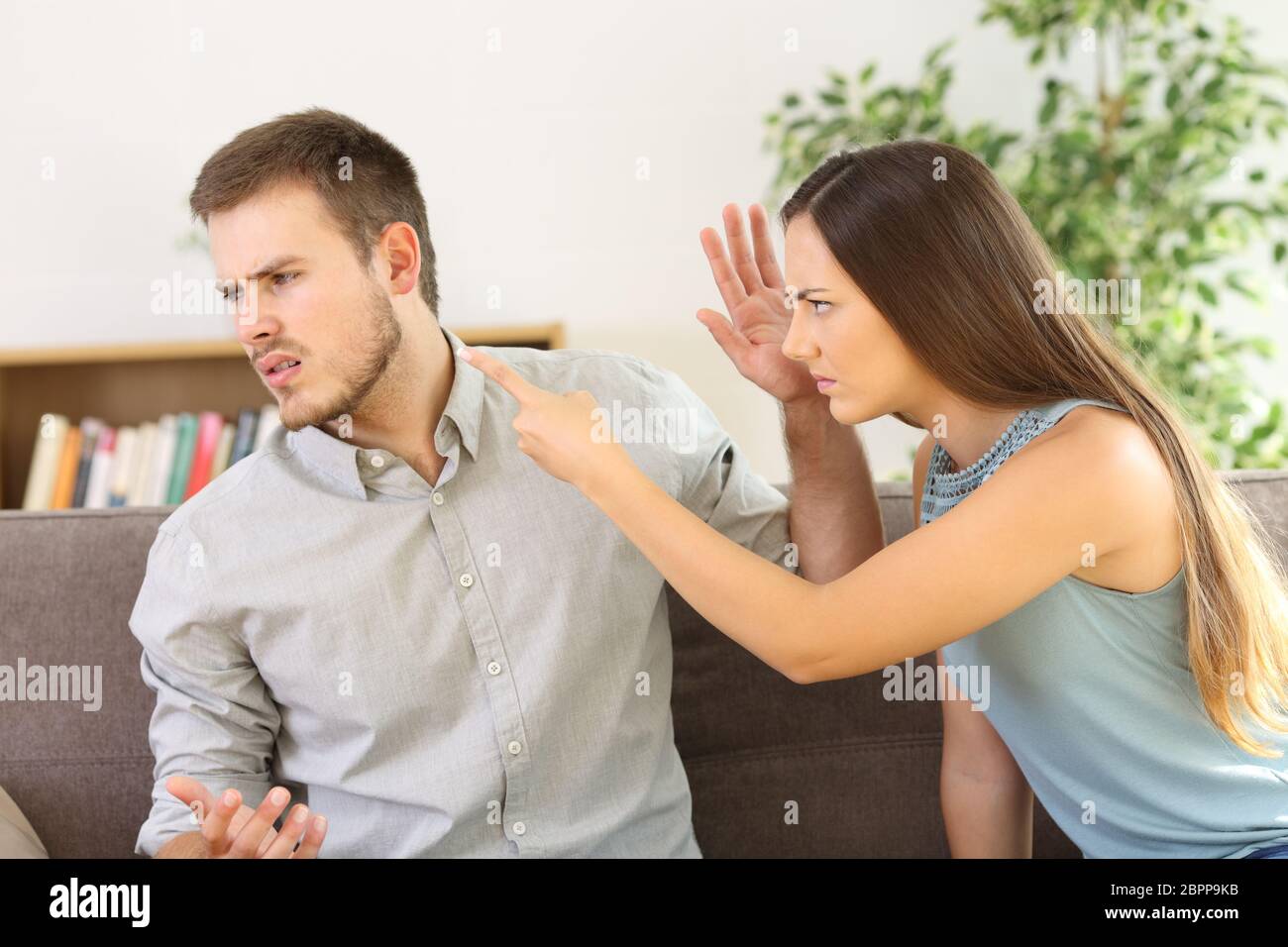 Angry couple arguing sitting on a sofa at home Stock Photo - Alamy