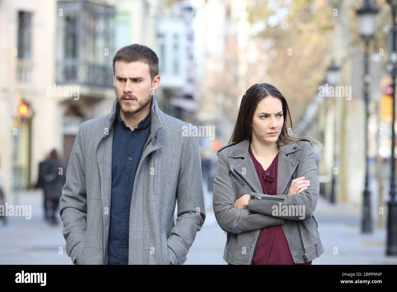 Front view portrait of an angry couple walking in the street after ...