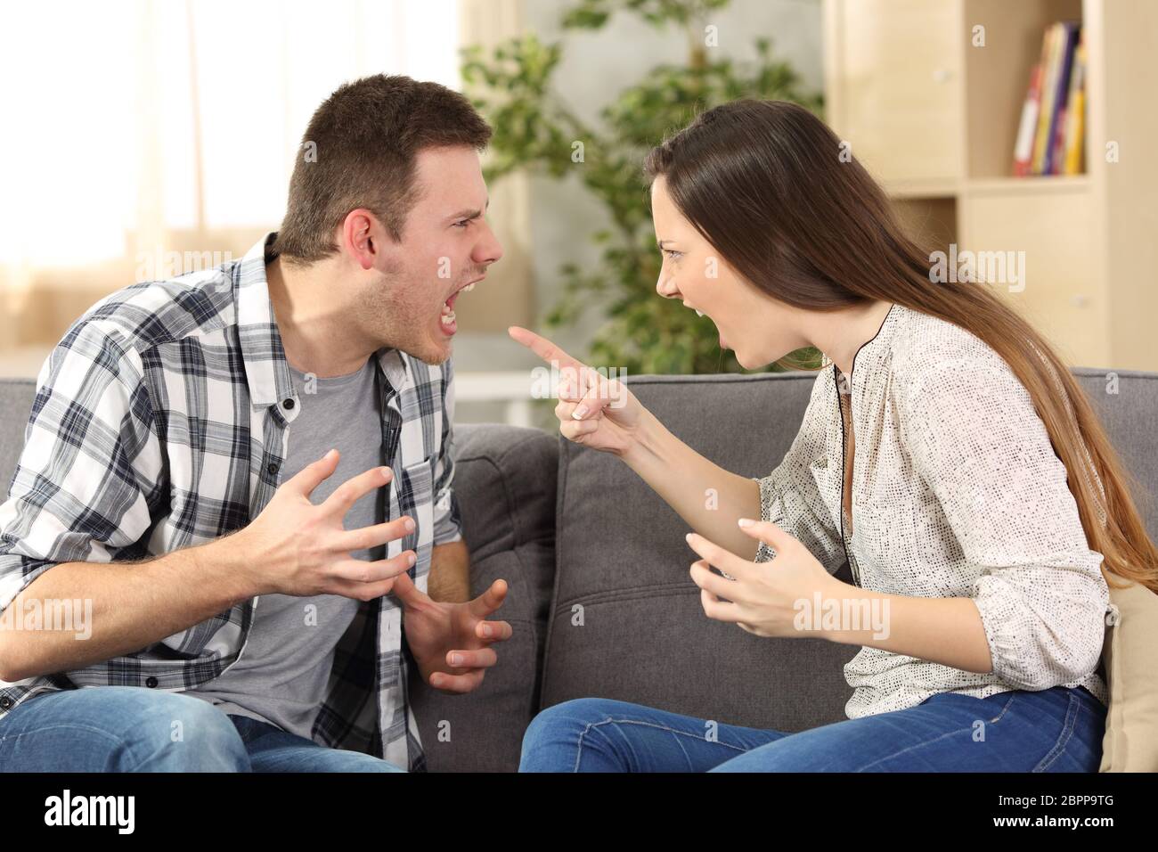 Couple arguing and screaming each other sitting on a sofa in the living ...