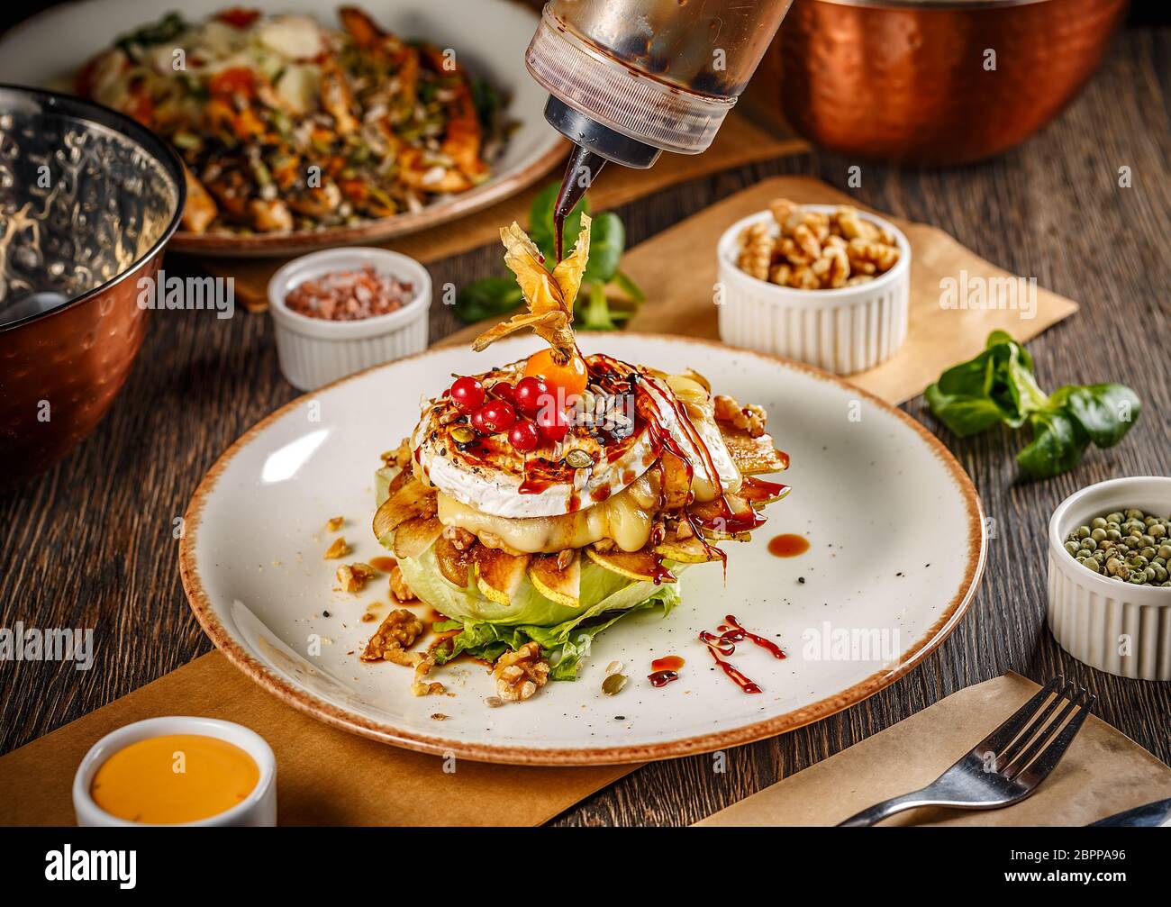 Grilled camembert cheese with walnuts and grilled pear on white plate ...