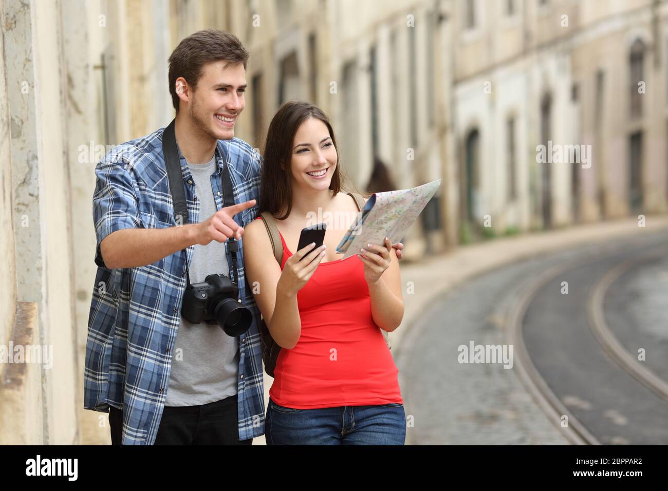 Couple of happy tourists sightseeing comparing online guide and map in ...