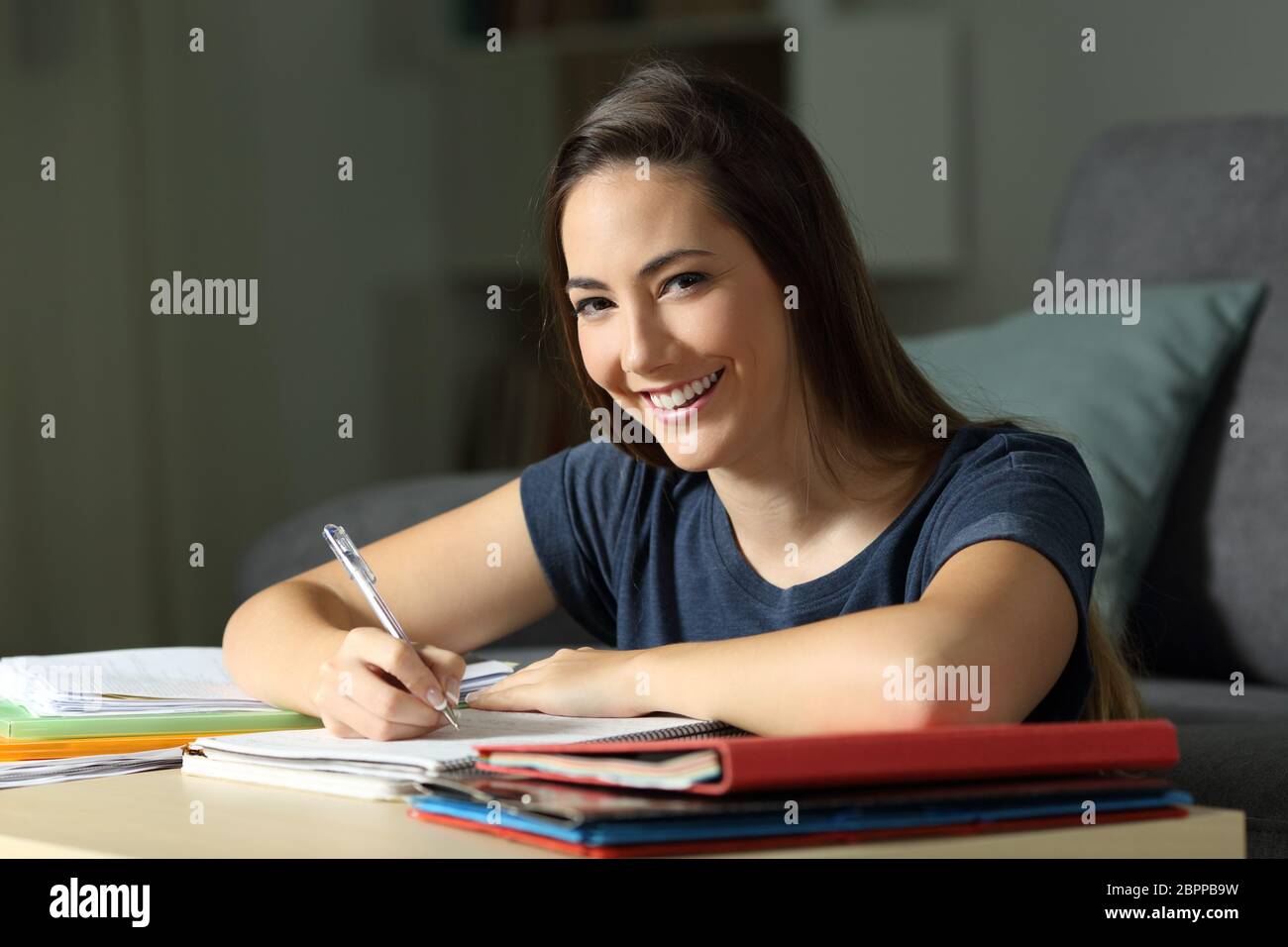 Happy student studying late hours in the night looking at you at home ...