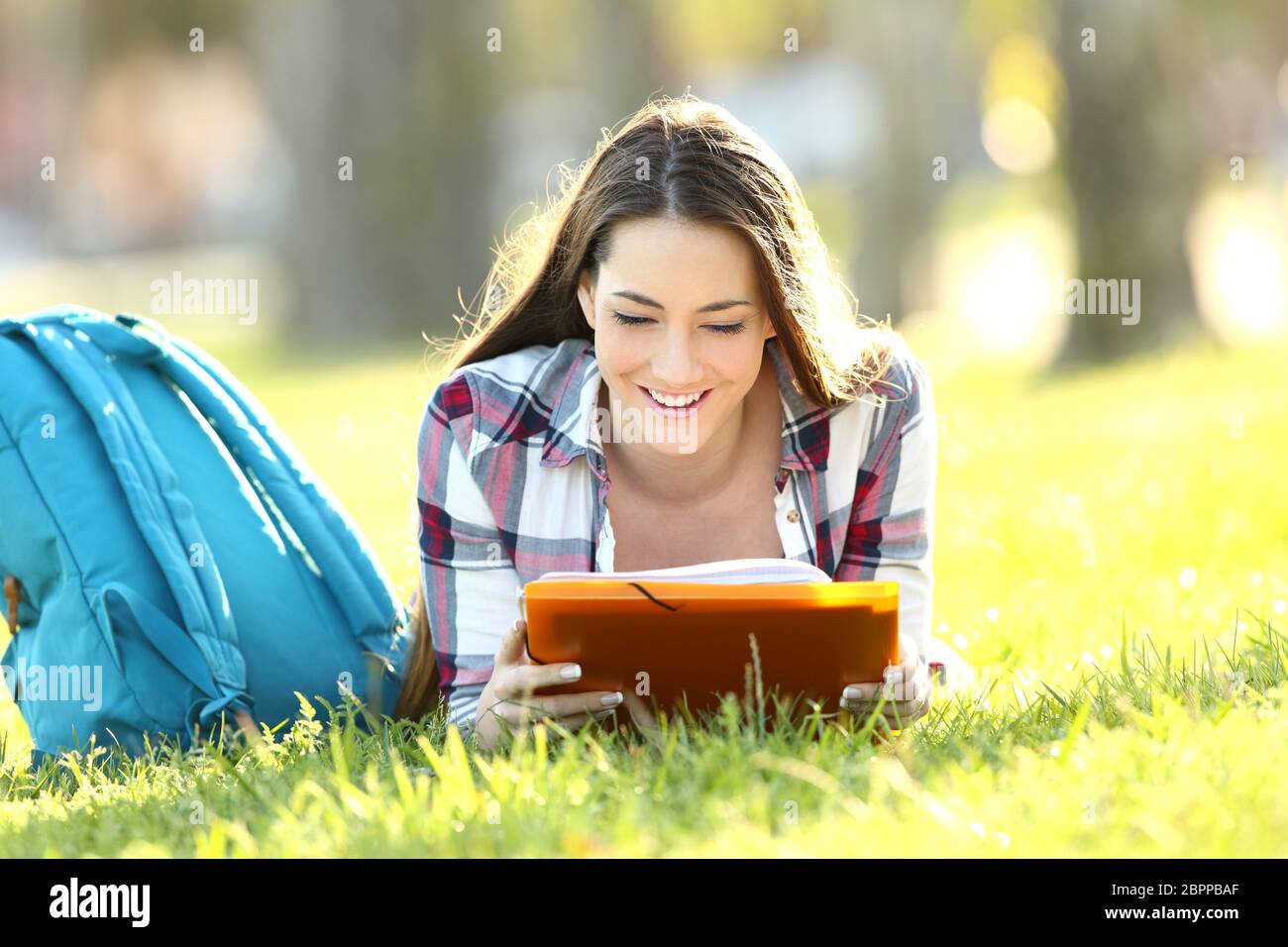 Single student girl learning reading paper notes lying on the grass of ...